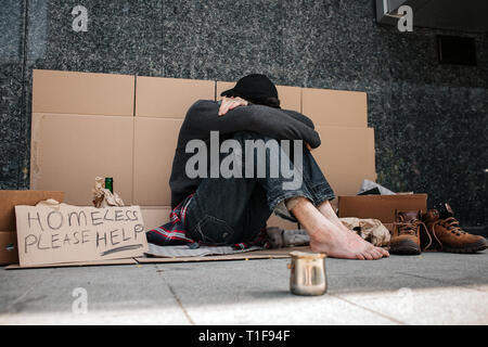 Man without shoes sitting down begging for money in winter, as people ...