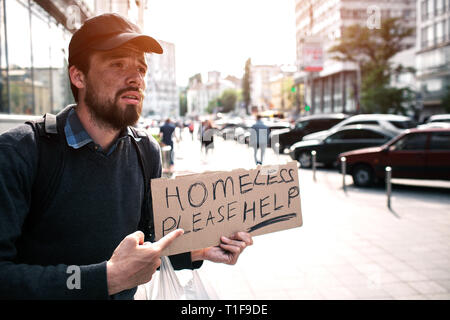 homeless man standing on cardboard and holding disposable cup Stock ...