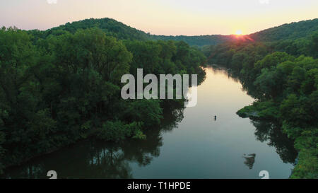 Aerial view of fisherman wading into calm Zumbro River at sunset, with ...