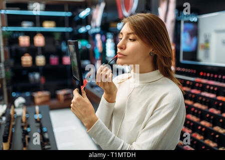 Female customer testing lip liner in the make-up shop. Cosmetics ...