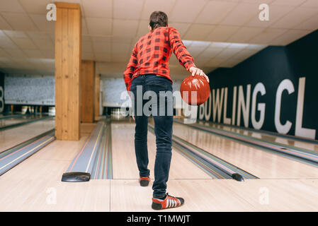Male bowler throws ball on lane, back view. Bowling alley player ...