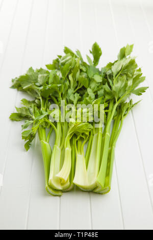 Bunch of fresh celery stalk on wooden table and cutting board and knife ...
