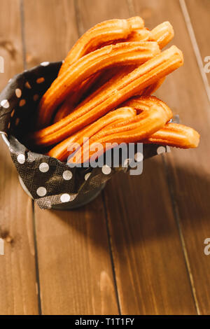 spanish fritters served on a wooden table with a cup of hot chocolate ...