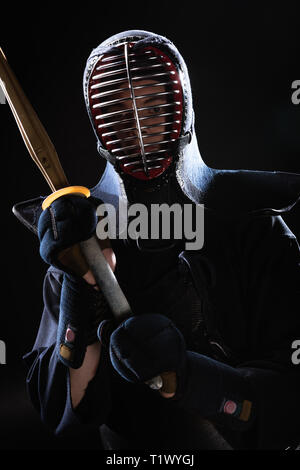 Kendo fighter in helmet holding bamboo sword on black Stock Photo - Alamy