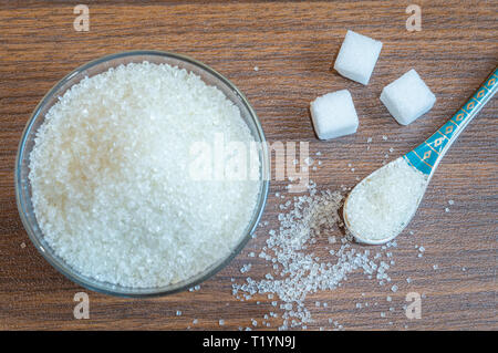White sugar kept in a glass bowl with a spoon. Some sugar cubes kept on ...