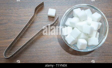 White sugar kept in a glass bowl with a spoon. Some sugar cubes kept on ...