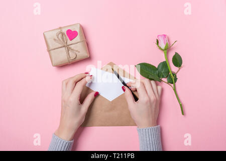 Craft envelope with blank paper, pen and red heart on beige background ...