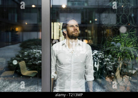 Pensative business man looking outside of large window front in modern ...