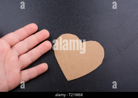 Hand is beside a heart shaped object on black Stock Photo - Alamy