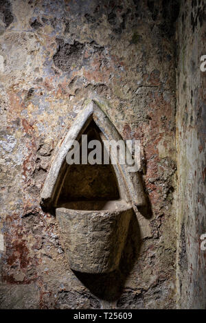 The Holy Water stoup in the ornate gothic cloister arcade arches of the ...