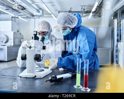 Chemists working in industrial laboratory, wearing protective clothing ...