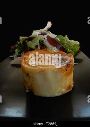 Fresh pecorino cheese gratin with duck ham and assorted salad, typical ...