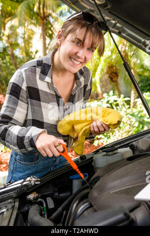 Smiling young adult woman checking her cell phone and holding a ...