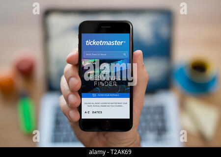 A man looks at his iPhone which displays the Ticketmaster logo, while ...