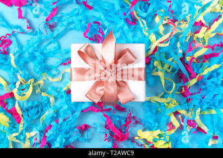 Gift box with colored streamers bright yellow background. A top view of ...