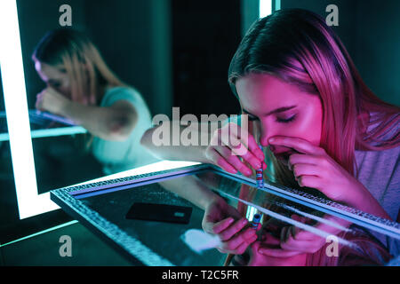 Drugs destroy your life. Young drug addict takes cocaine with rolled ...