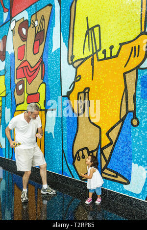 Adult men interact with children in an outdoor setting, demonstrating ...