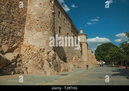 Pedestrian promenade beside large city wall with quaint stone tower at ...