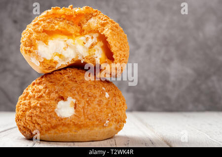two pieces sweet puffs and one with a bite on a white wood table Stock ...
