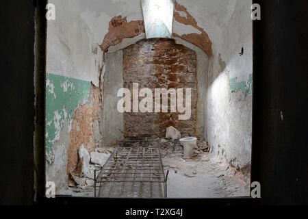 Interior of solitary confinement cell with metal bed, desk and toilet ...