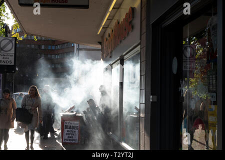 Man vaping by a newspaper stand on a street corner in Sheffield, with ...