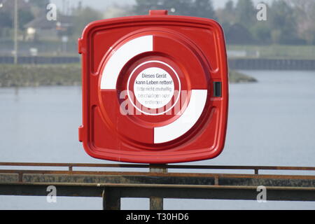 Red lifebuoy in a container on a railing at a body of water Stock Photo ...
