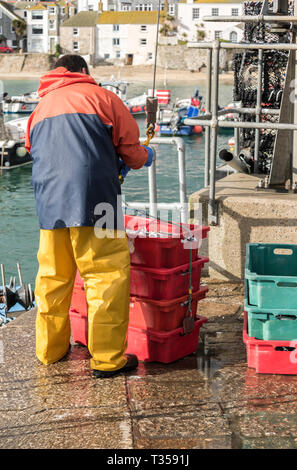 Cornish fisherman landing his catch in a dinghy, Newquay Harbour ...