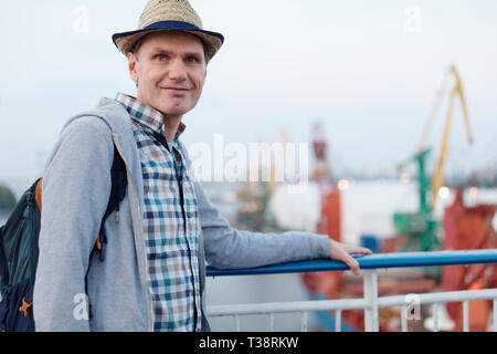 Handsome tourist in straw hat, covering face from sun and looking at ...