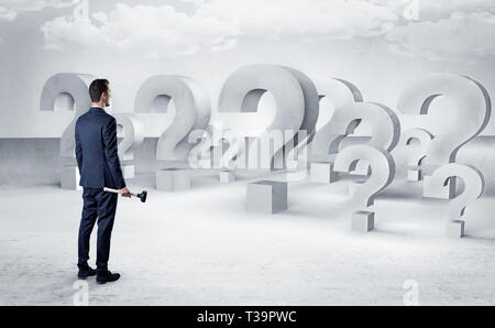 Businessman standing and looking to a bunch of question mark signs ...