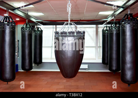 Empty modern fight club with punching bags of different shapes for ...