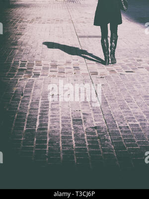 Rear view of a woman wearing a black jacket and jeans walking in a ...