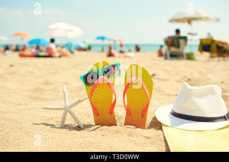 Summer slippers on the beach near the water. Sea shells on a sunny day ...
