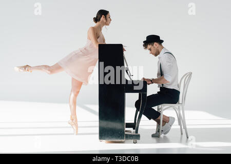 handsome pianist playing while beautiful ballerina dancing near piano ...