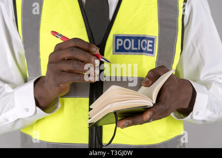 British Police officer writing notes in his pocket book wearing a ...