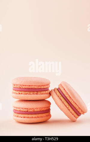 Stack of pink macarons with berry filling on same color background ...