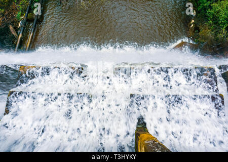 Looking down at the flow of water falling over a concrete dam, San ...