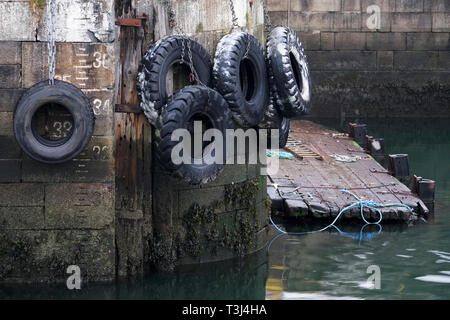 Car tyres hanging on rope against harbour wall at port dock to protect ...