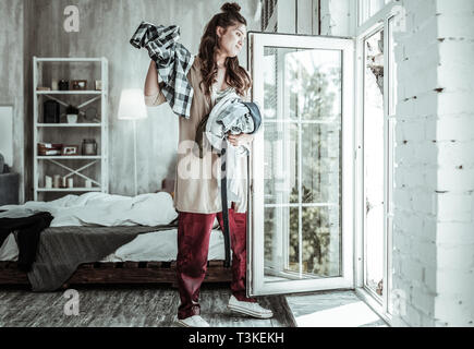 Woman throwing clothes by the window Stock Photo - Alamy