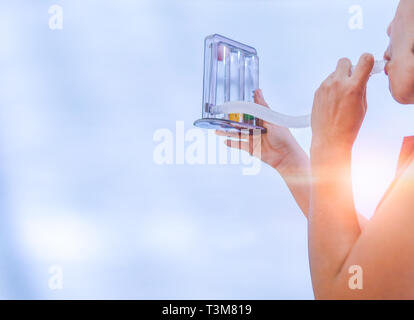woman holding triflow and deep breathing to improve lung expansion ...