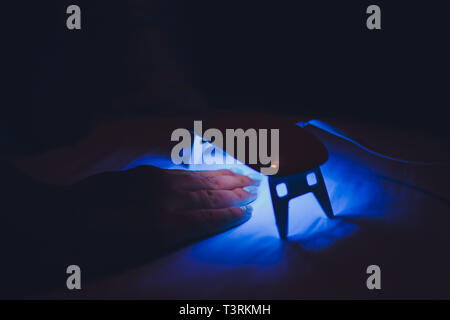 Woman includes lamp and dries her nails with shellac in UV lamp. Close ...