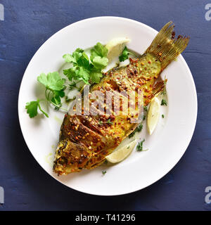 Baked fish on plate over black stone background. Close up view Stock ...