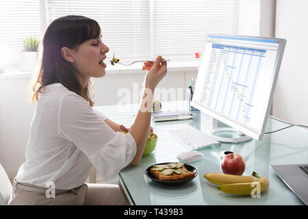 Eating breakfast at work in front of computer screen Stock Photo - Alamy