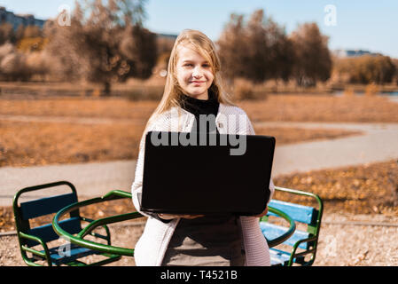 beautiful student sits on the carousel for a laptop. student doing ...