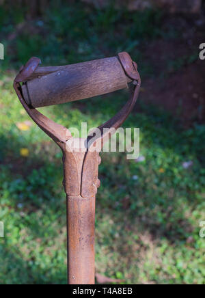 Damaged handle of a retro garden tool isolated against a green ...