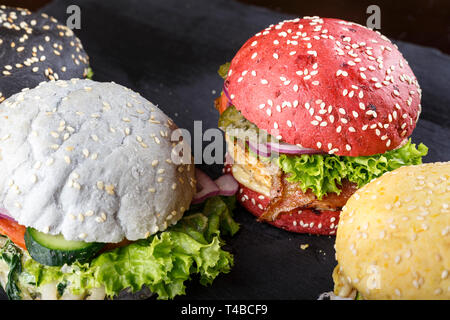 Multi colored burgers on wooden plate selective focus Stock Photo - Alamy