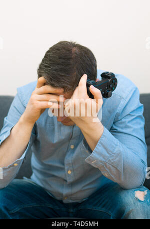 Sad man with gamepad in hands playing video game Stock Photo - Alamy