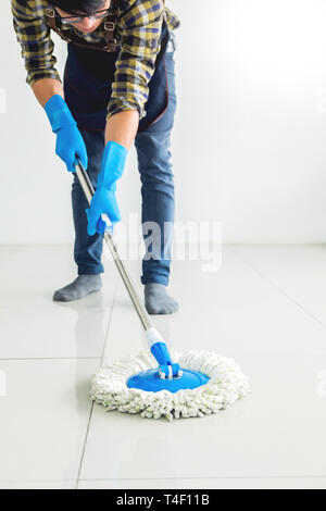 Young housekeeper cleaning floor mobbing holding mop and plastic bucket ...