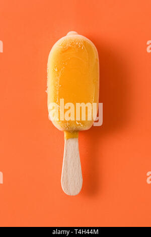 top view orange color popsicle with some bites on an orange color ...