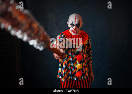 Scary bloody clown reaches out baseball bat. Man with makeup in ...