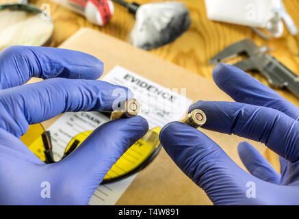 Expert police officer comparing two nine millimeters bullets in ...